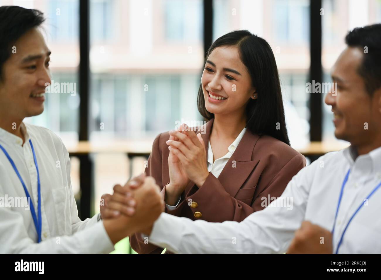 Smiling businesswoman clapping hands while businesspeople stacking ...
