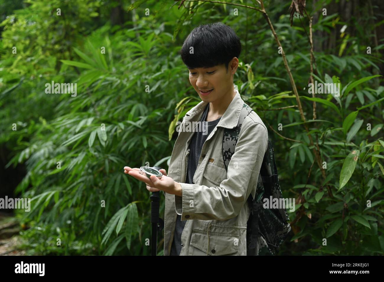 Male hiker using compass for directions in the forest, enjoying his ...