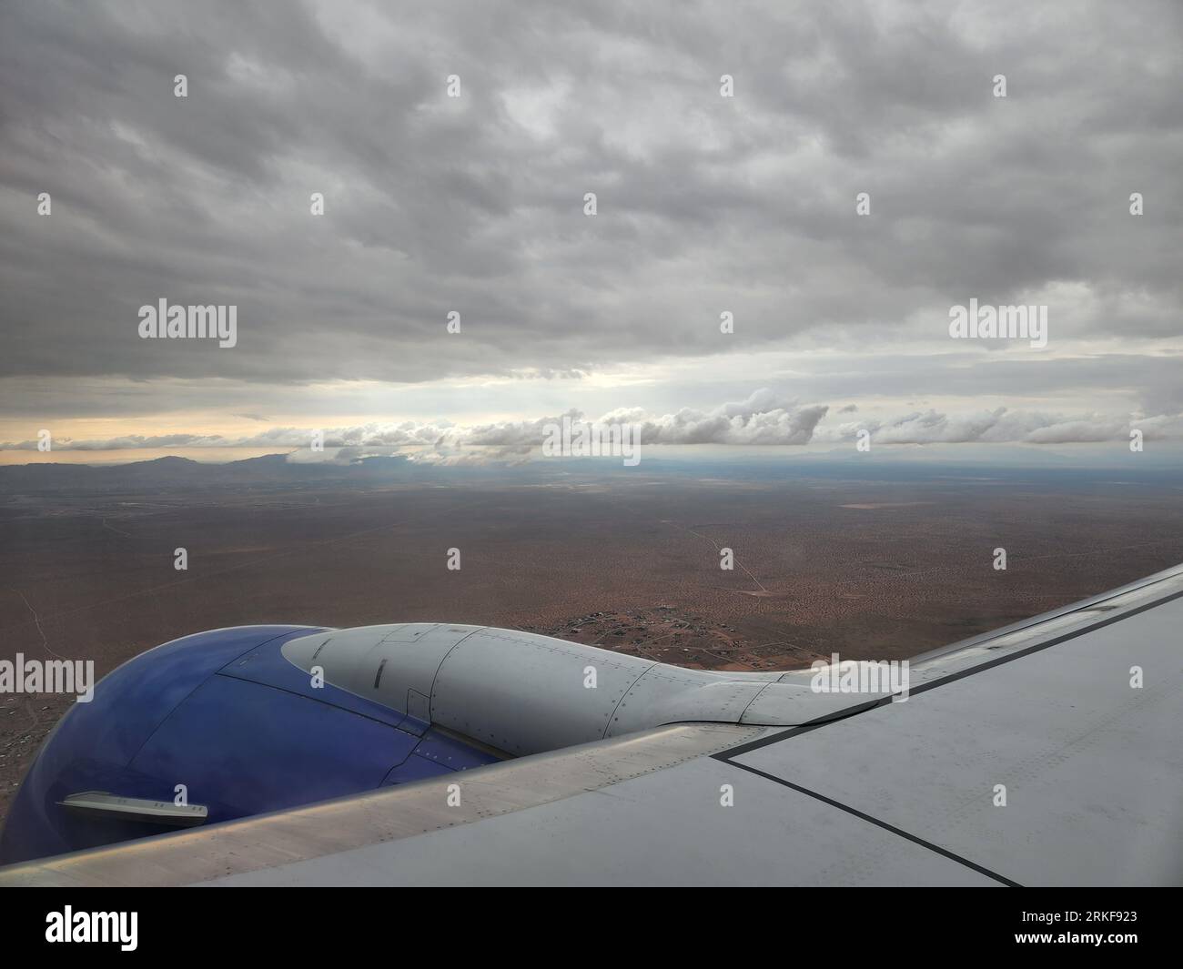 An aerial view of a commercial aircraft flying over desert terrain ...