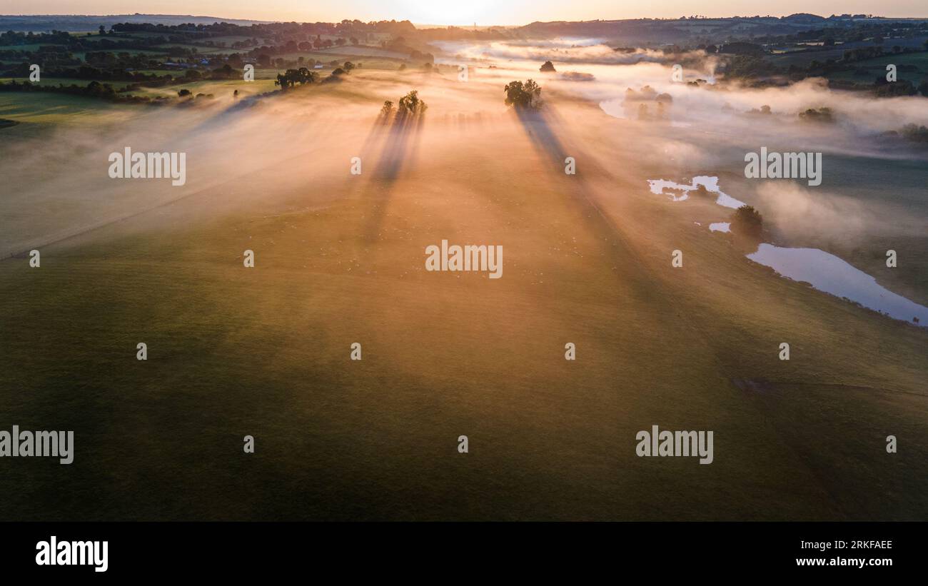An aerial view of a pastoral landscape covered with fog at golden hour ...