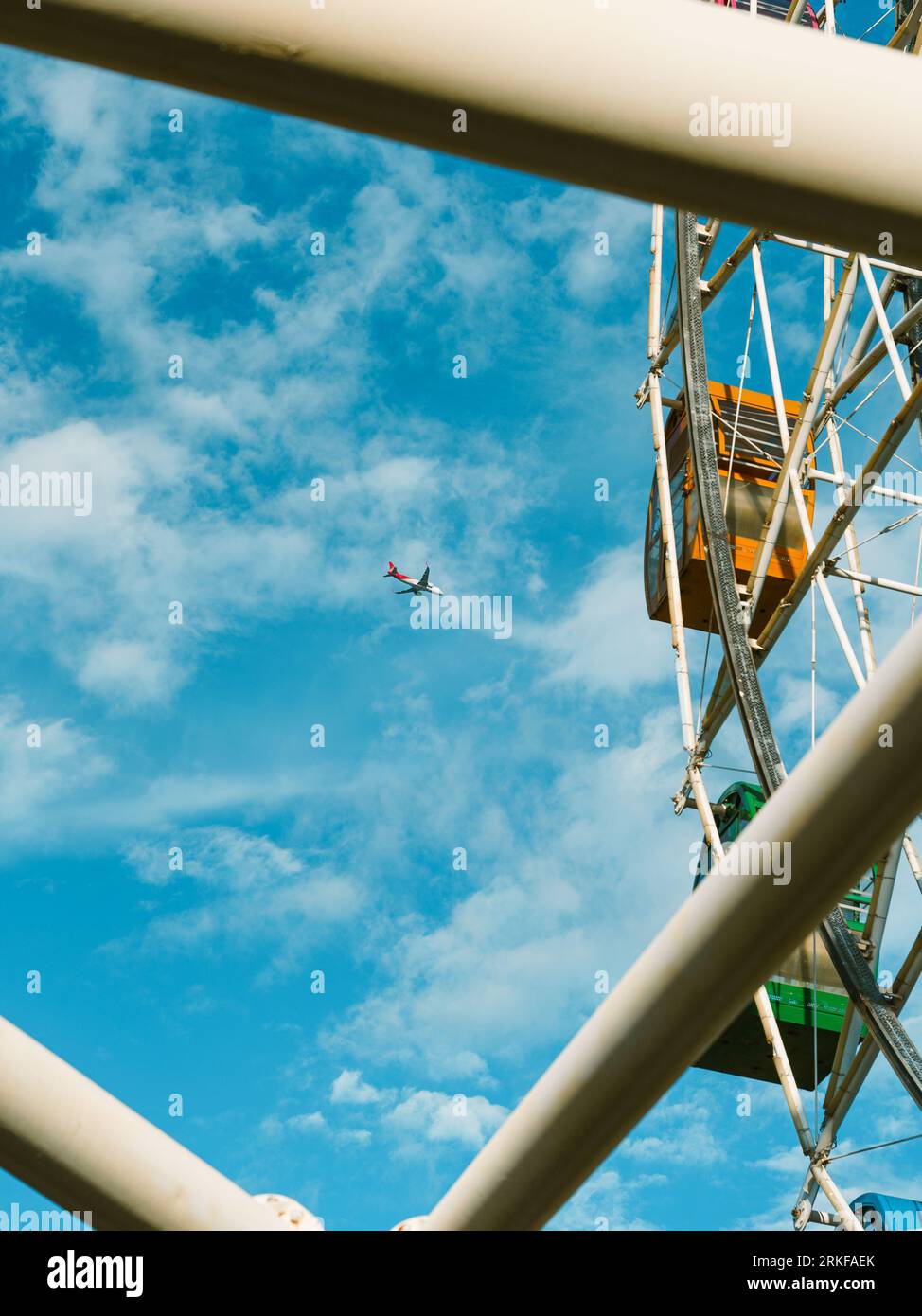 An airplane soars through the air above a traditional Ferris wheel ...