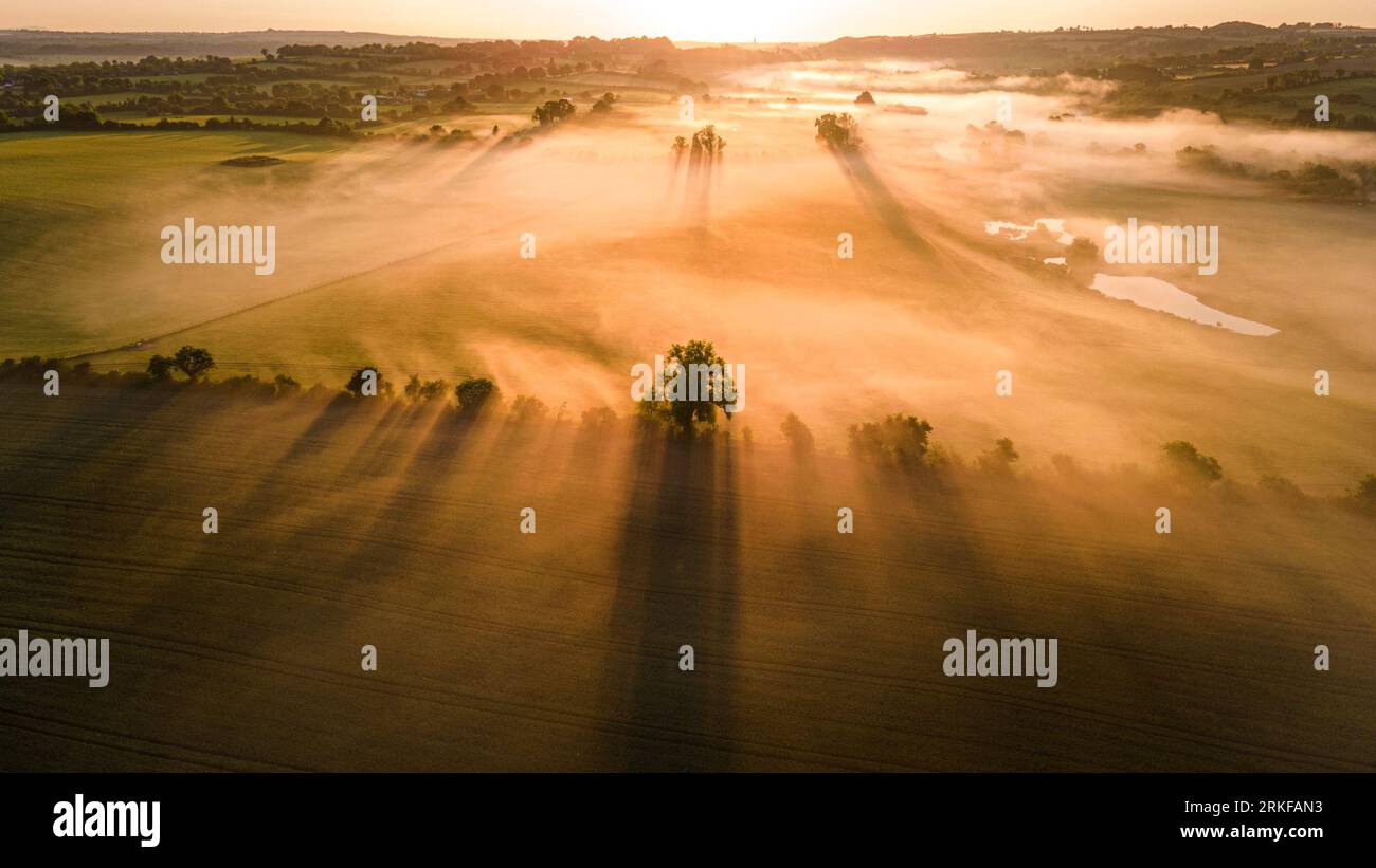 An aerial view of a pastoral landscape covered with fog at golden hour ...