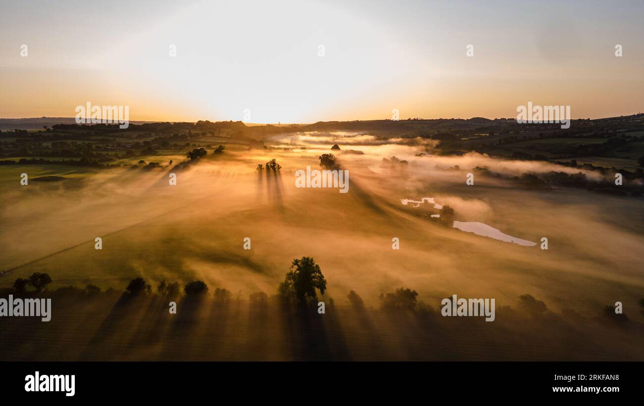An aerial view of a pastoral landscape covered with fog at golden hour ...