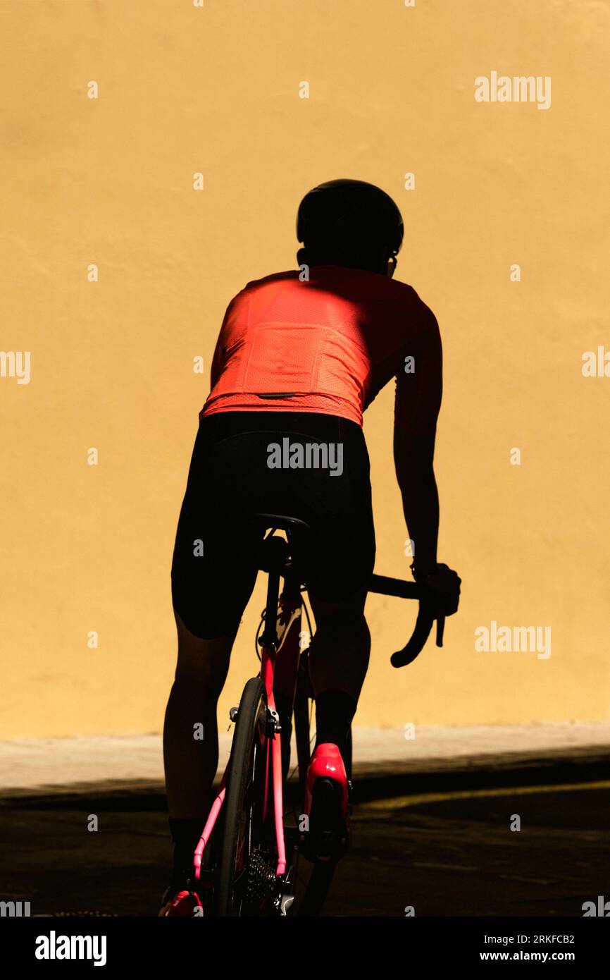 Minimalistic back view of cyclist in red against a yellow wall Stock ...
