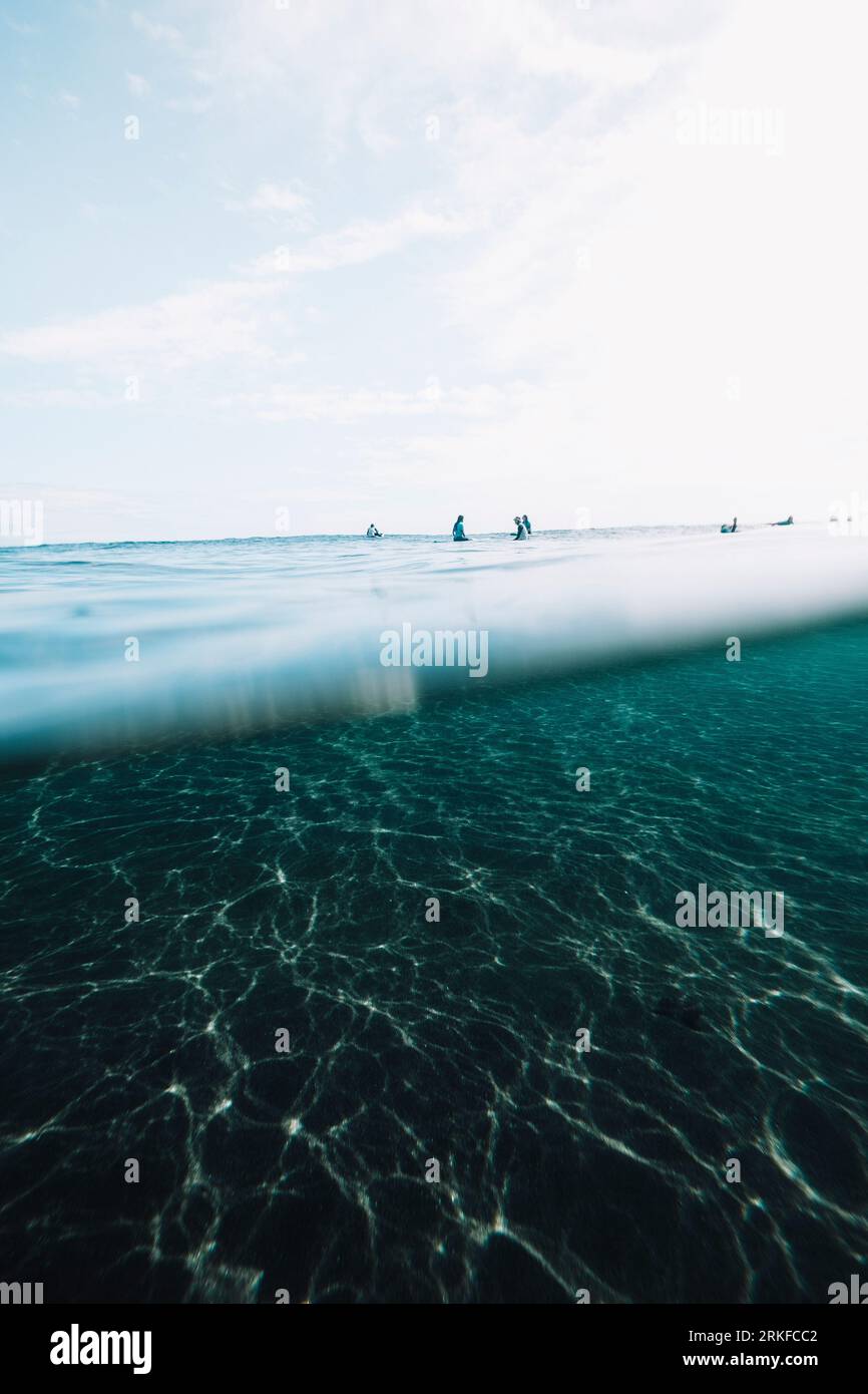 Pulled back over under of surfers waiting sitting on surfboard Stock ...