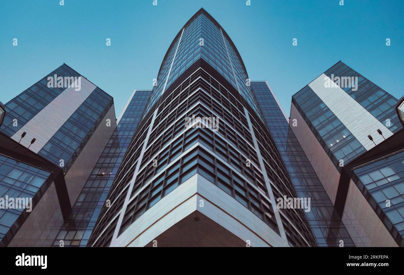 Bottom view of modern skyscrapers in business district against blue sky ...