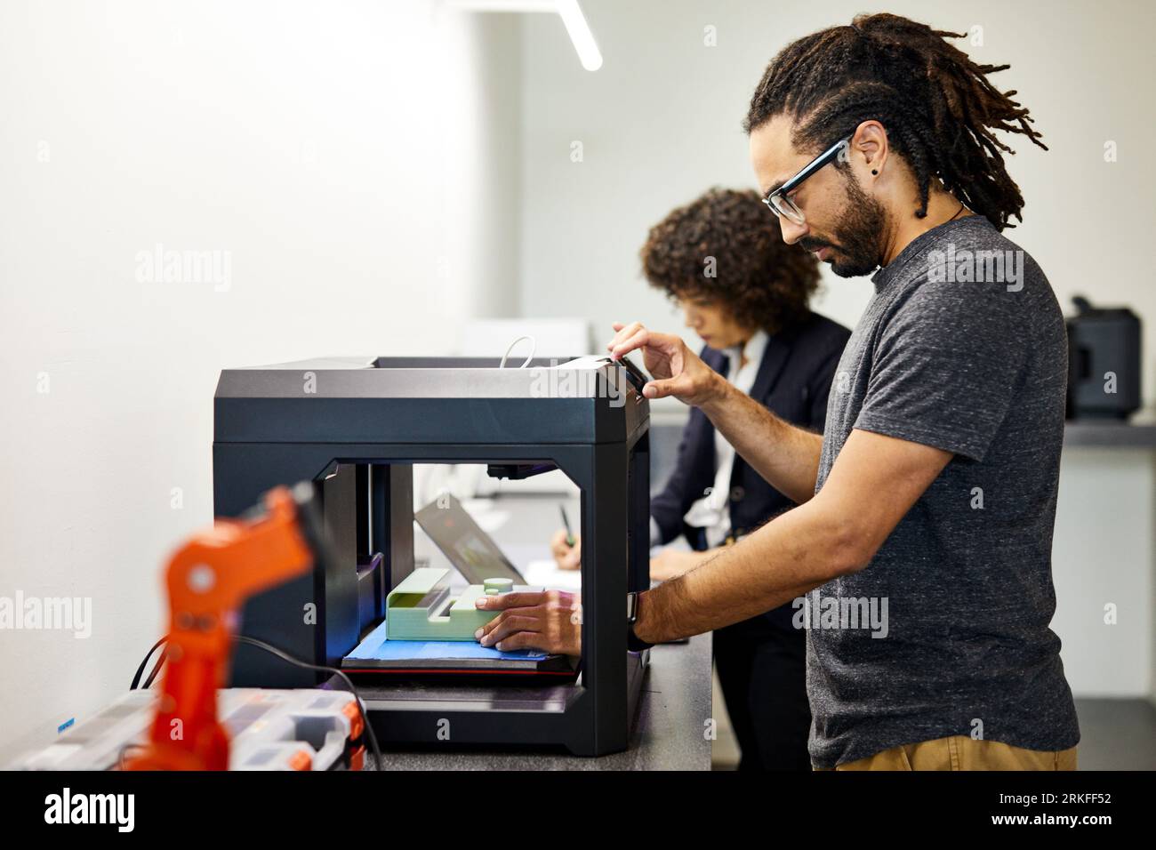 Side view of businessman examining model in 3D printer at office Stock ...
