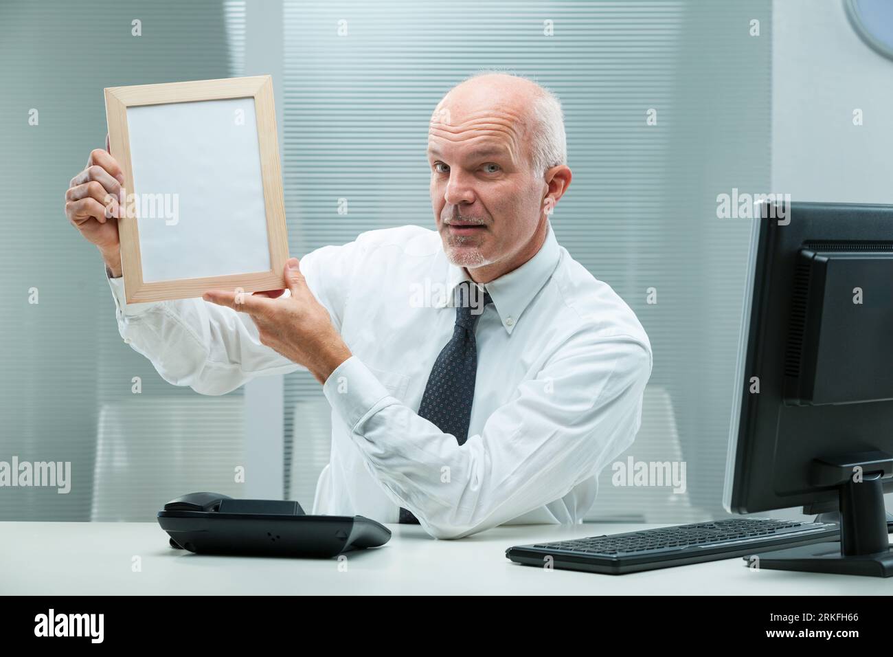 Senior man at work, dressed professionally, showcases an empty ...