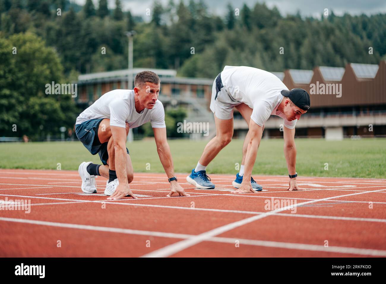 The two male athletes posed to run on a track in the sunshine Stock ...