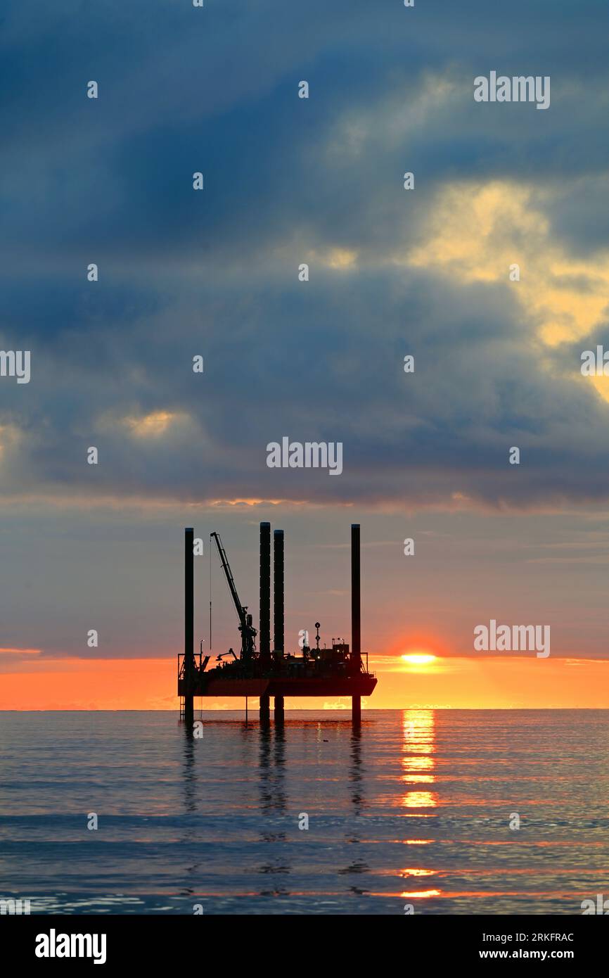 Drilling test rig with gold rimmed horizon cloud and orange sky and sun ...