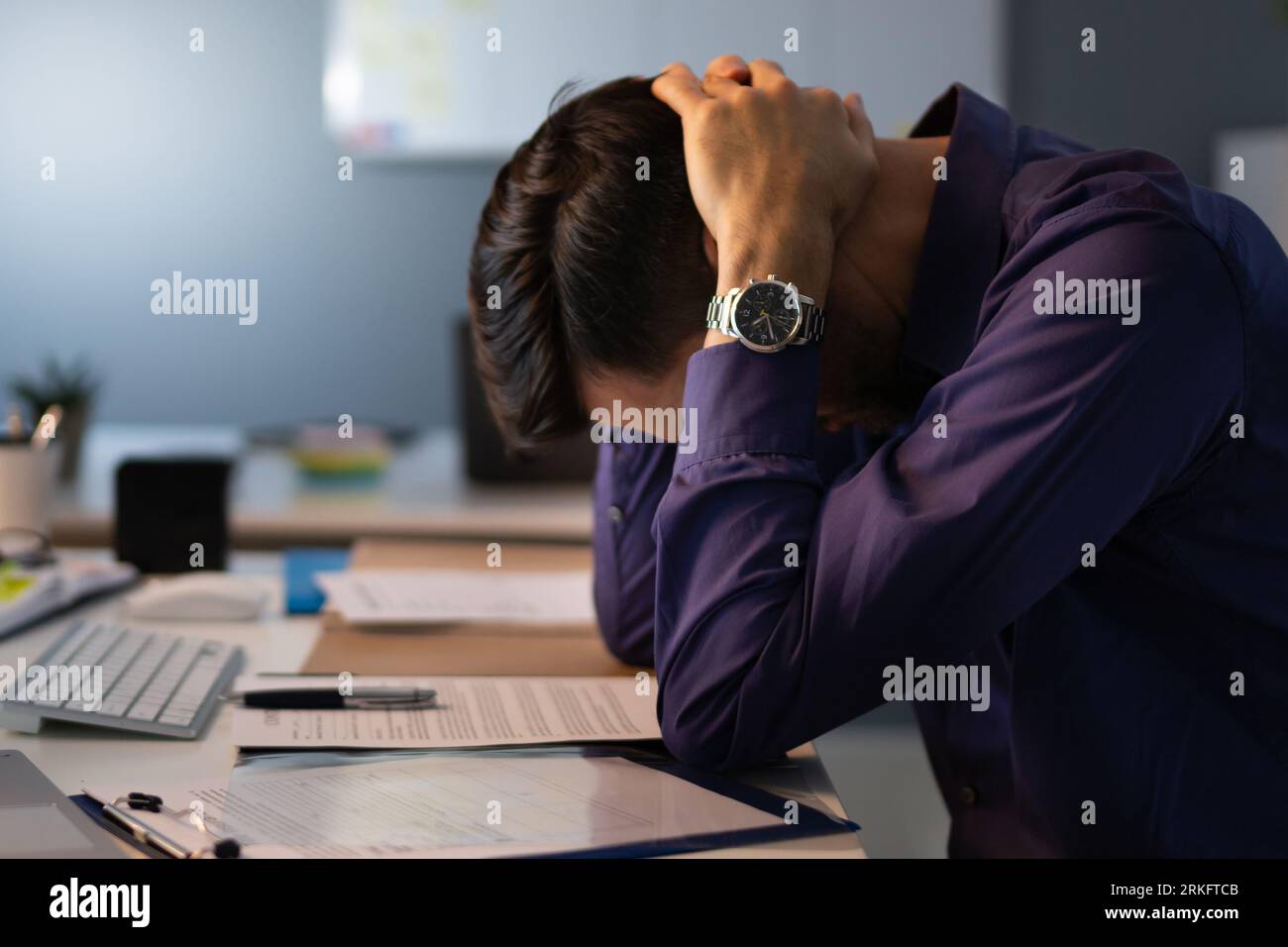 Stressed Accountant Sitting With Head In Hand While Working Late In ...
