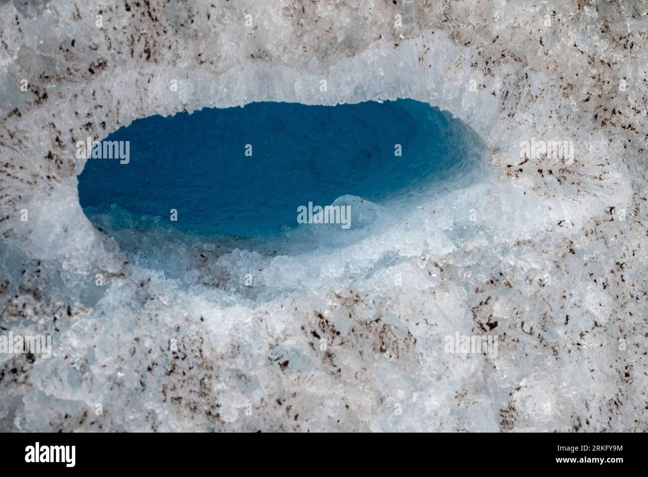 A small pool of water is suspended on the surface of a frozen lake ...