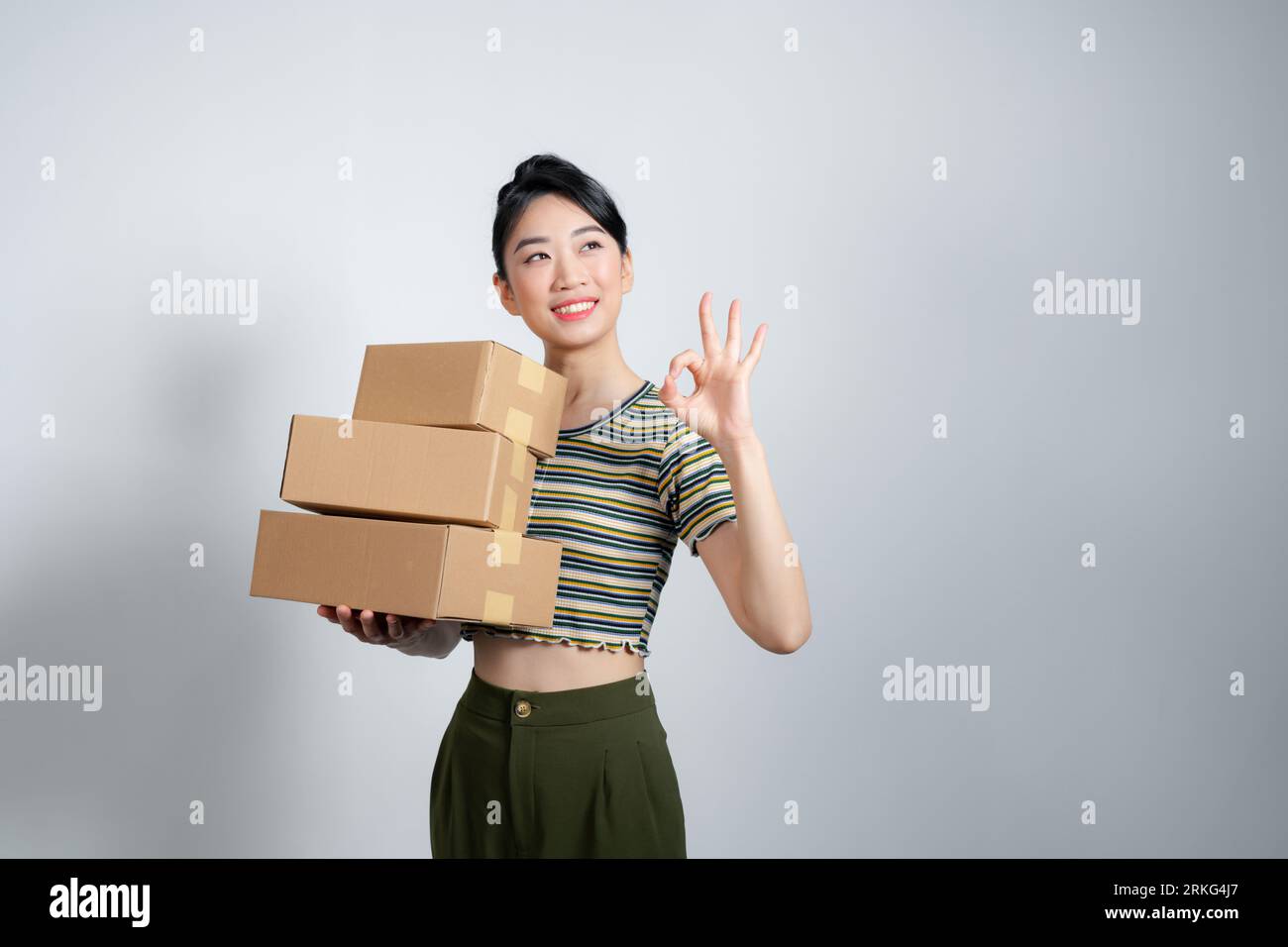 Businesswoman with carry delivery and showing okay sign, white background Stock Photo - Alamy