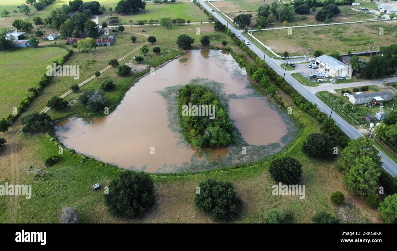 Aerial view of a large pond, with a winding road running alongside it ...