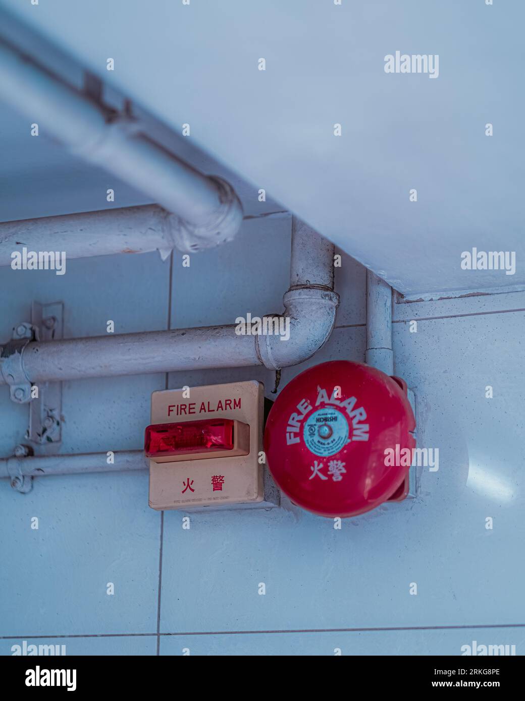 Fire bell alarm (red) with emergency light and pipeline on the wall ...