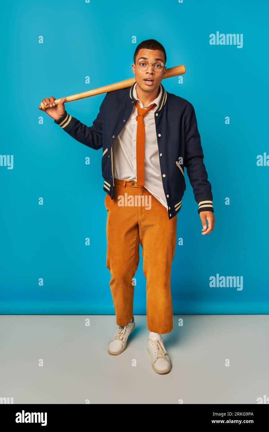 expressive african american student in orange pants holding baseball ...