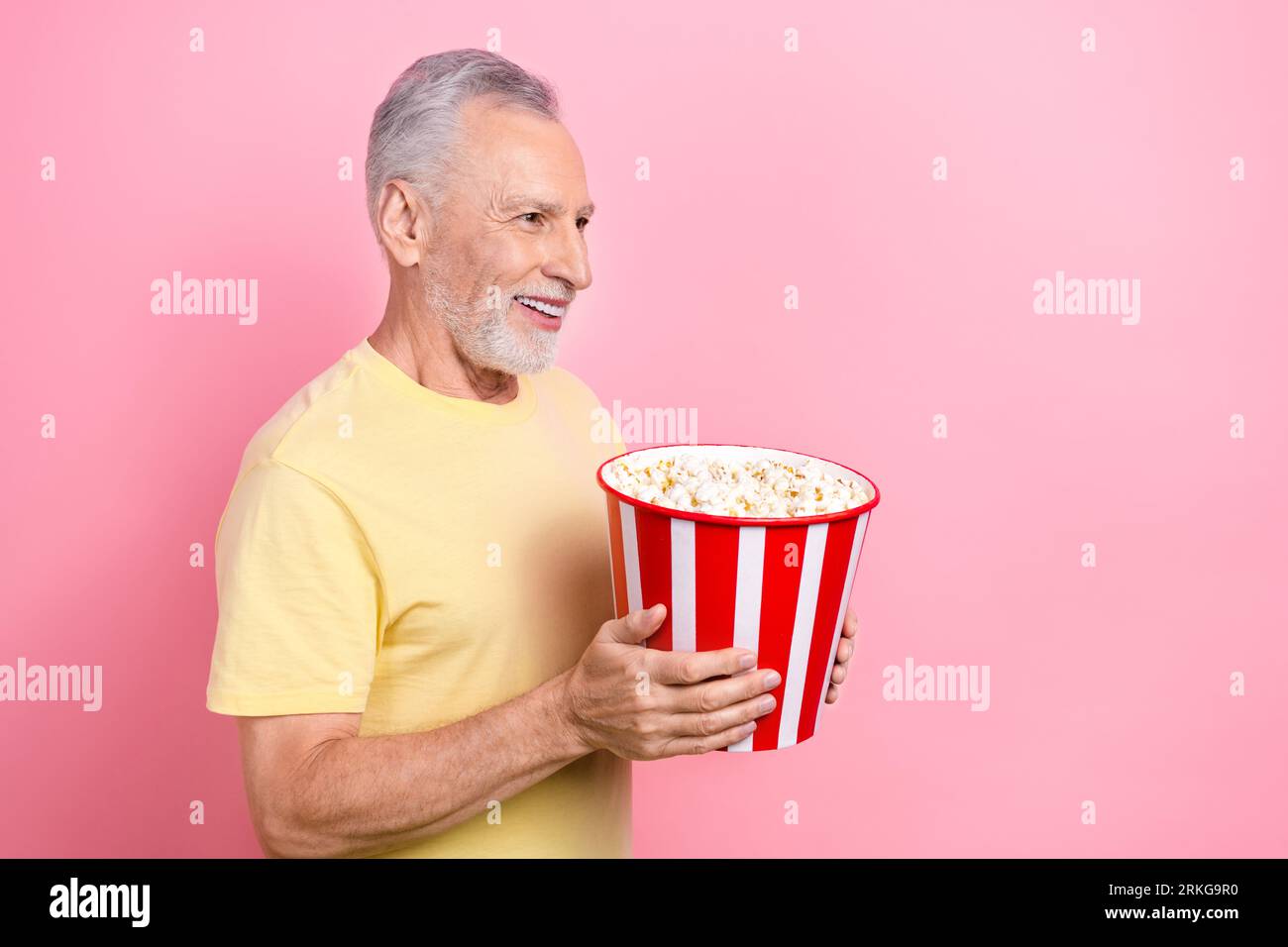 Photo of senior grey hair old man eating tasty bucket crisps looking ...