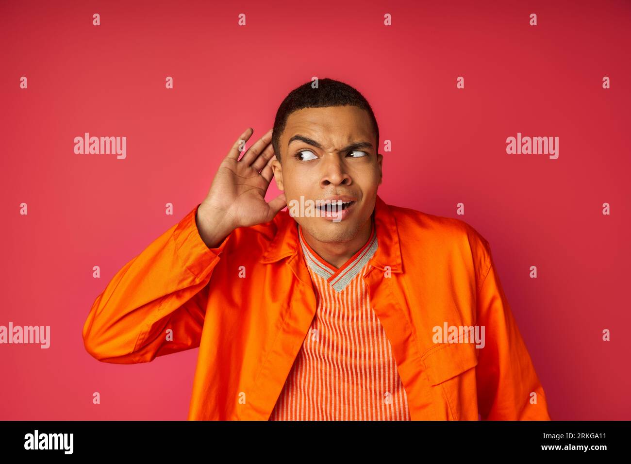 curious african american man with hand near ear eavesdropping on red ...