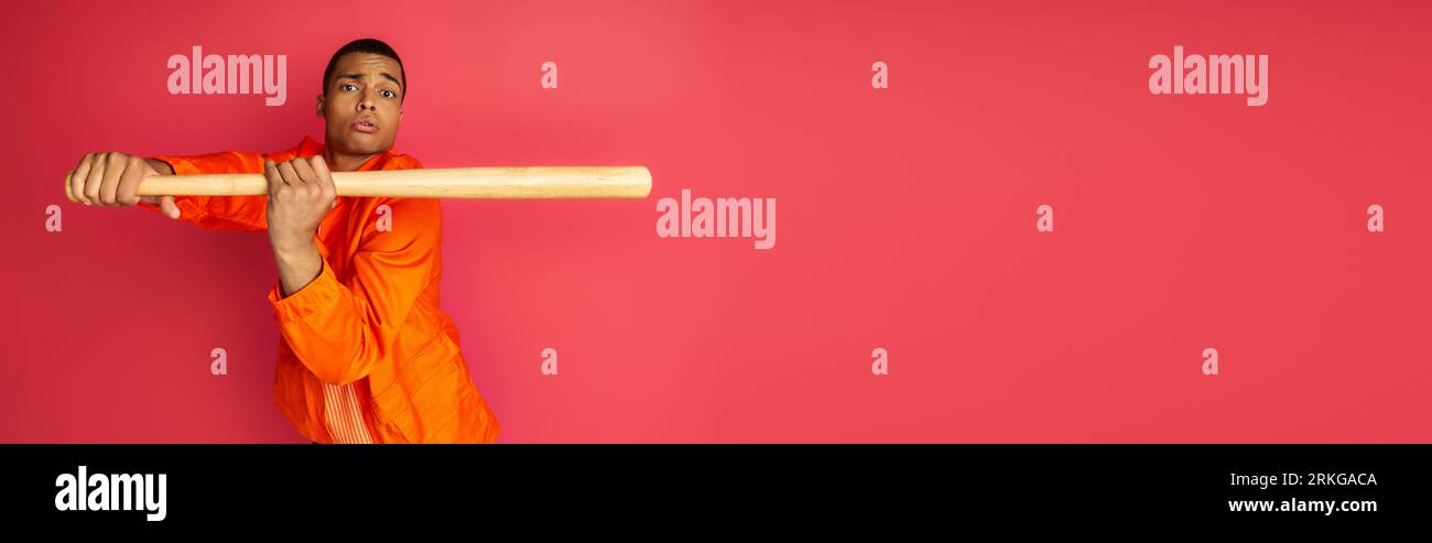 serious african american man in orange shirt playing baseball on red ...