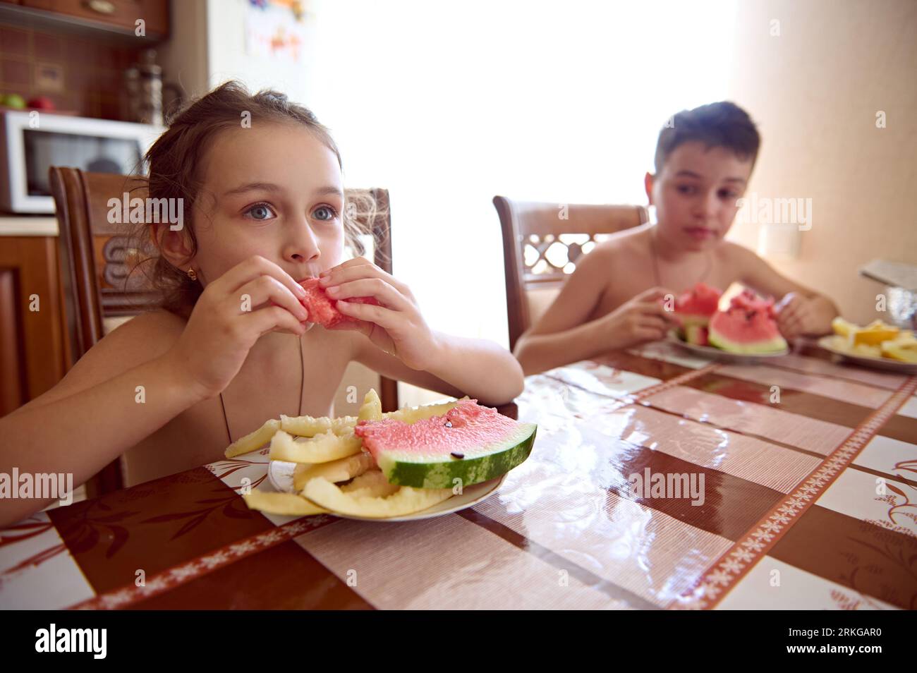 Adorable little kid girl snacking with a delicious tasty juicy ripe ...