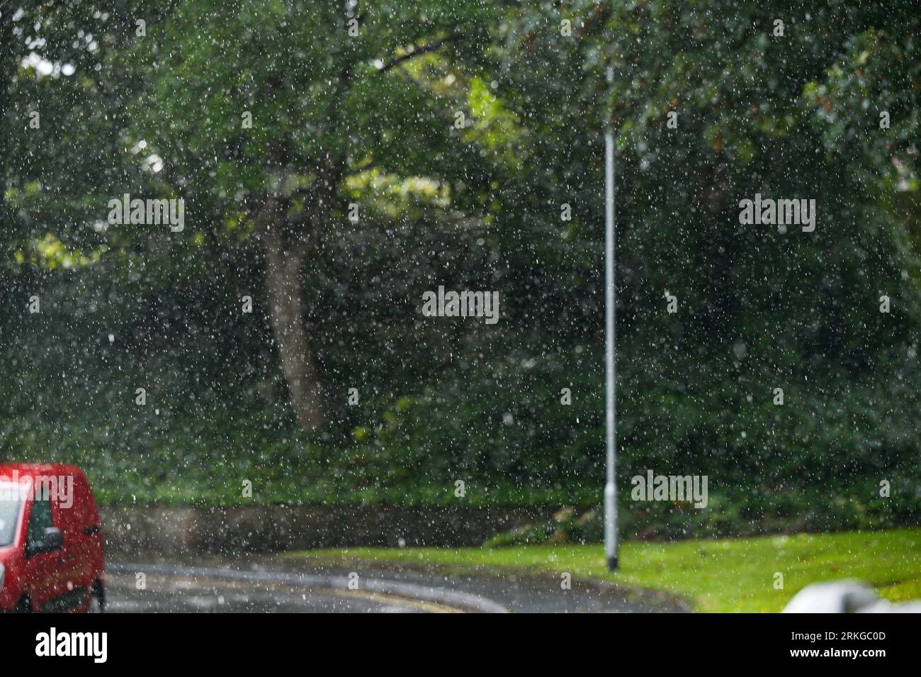 Summer rain raindrops during storm in urban street with parked cars ...