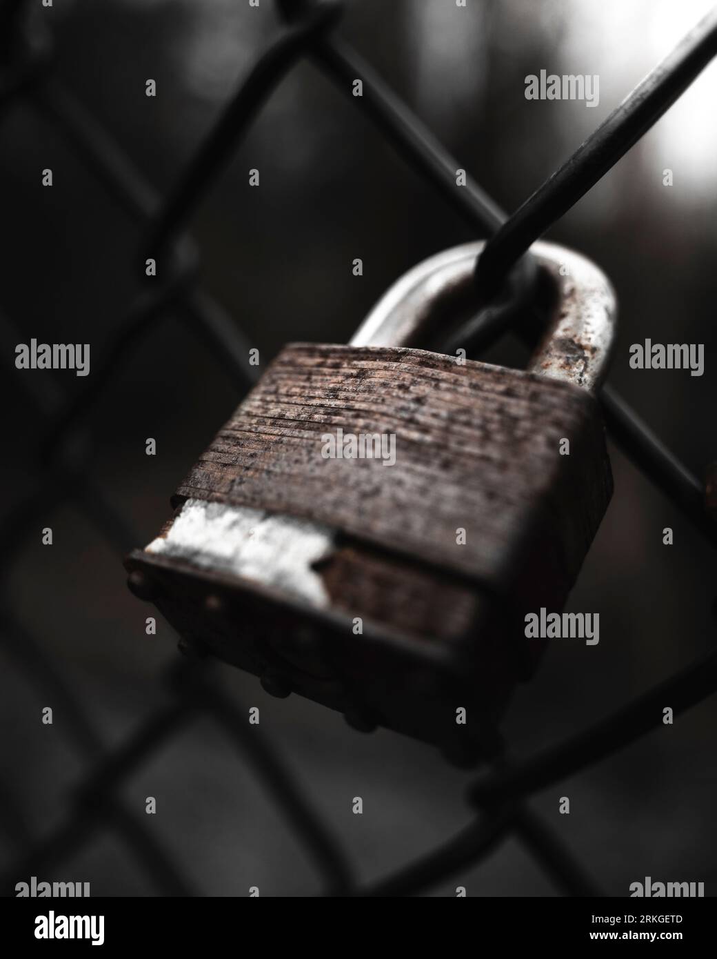 A closeup of a metal padlock hanging from a chain link fence, secured ...