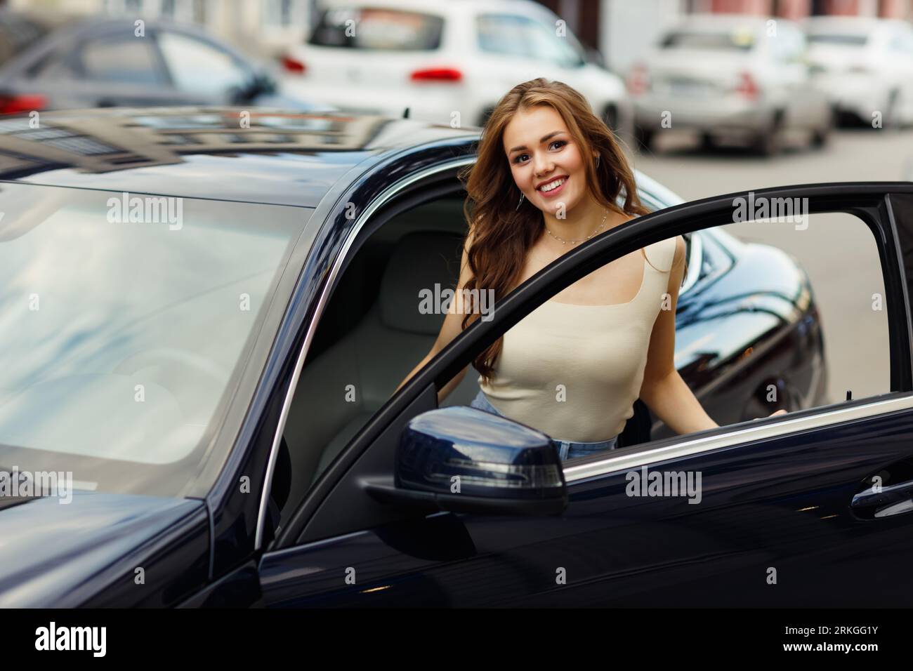 Happy woman driver entering car smiling. Cute young happy brunette ...