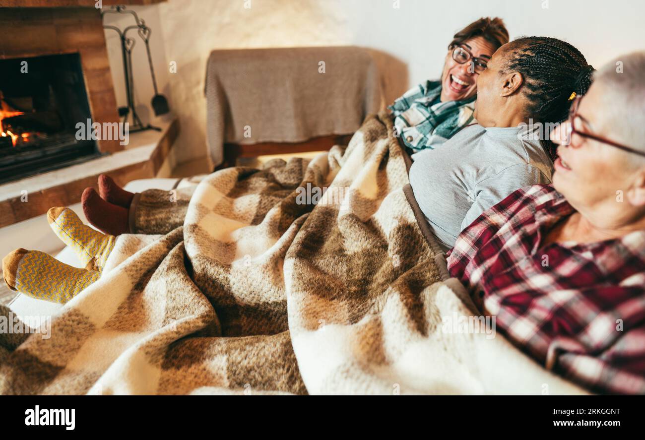 Multiracial women relaxing at home chalet in front of fireplace during ...