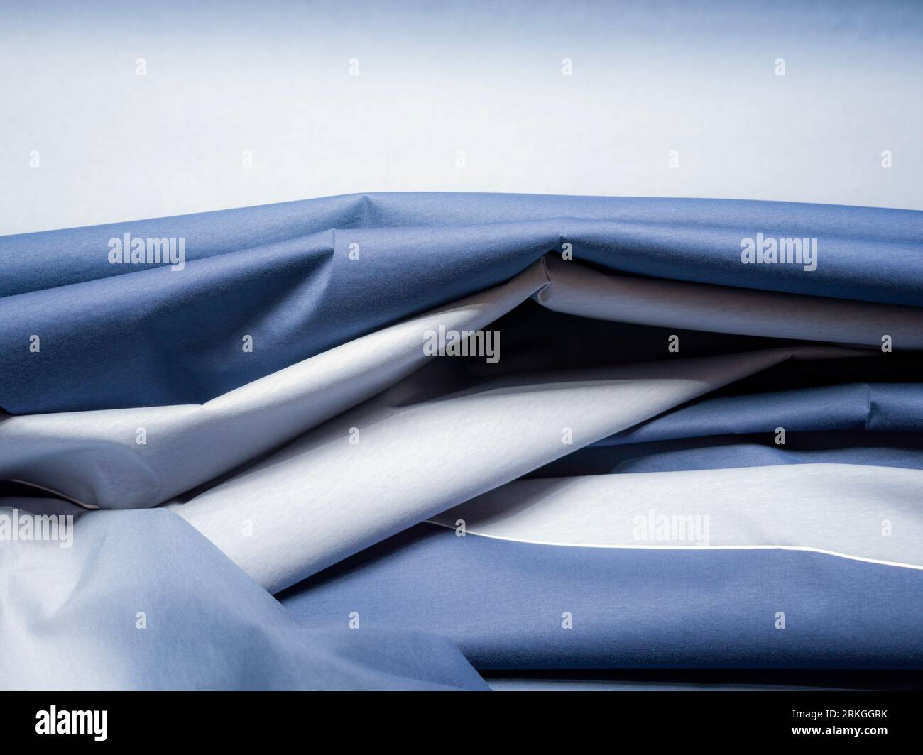 A stack of neatly folded white and blue fabric sheets in a pile Stock ...