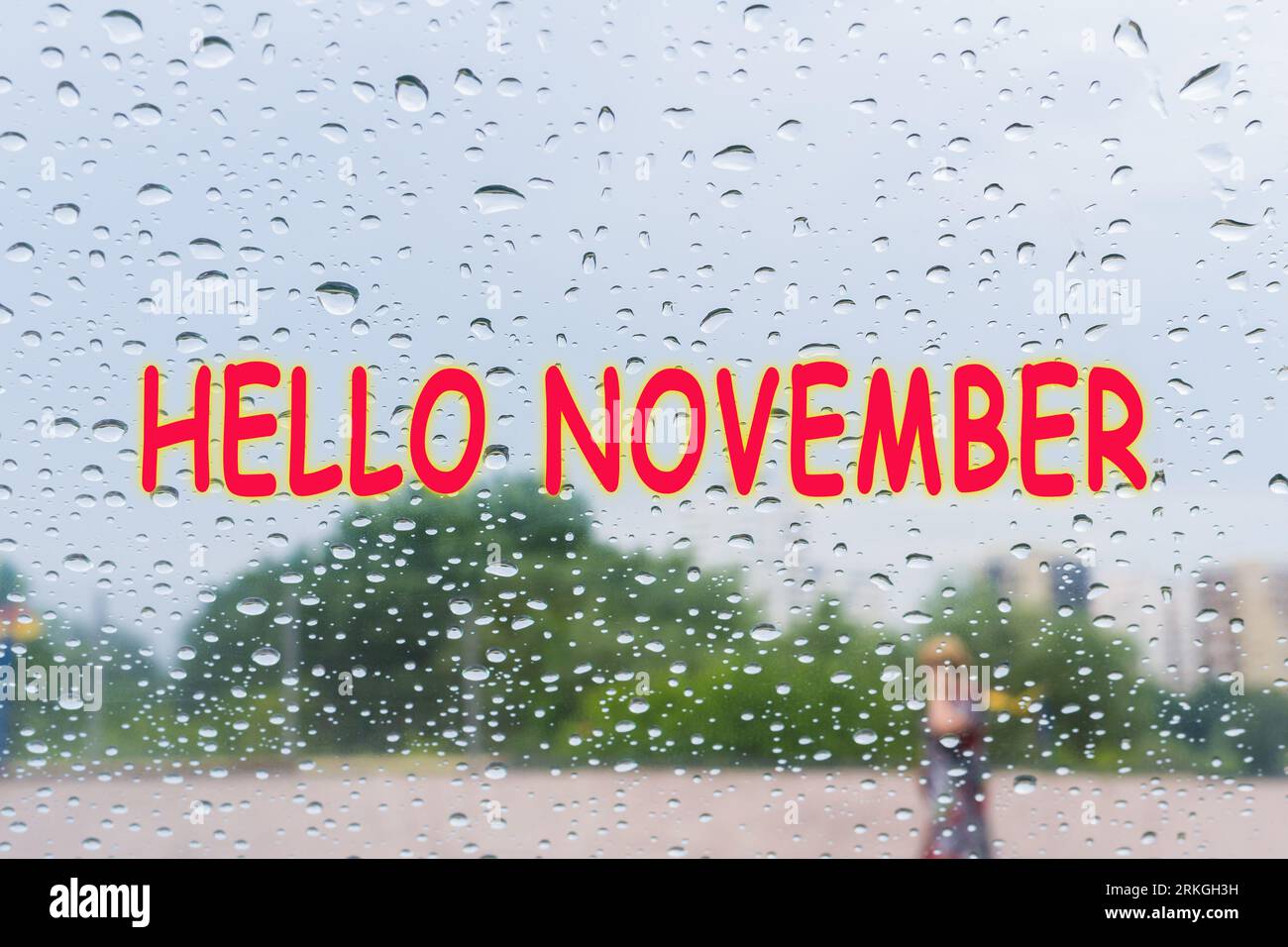 Nature background with lettering Hello November. Rain drops on glass ...
