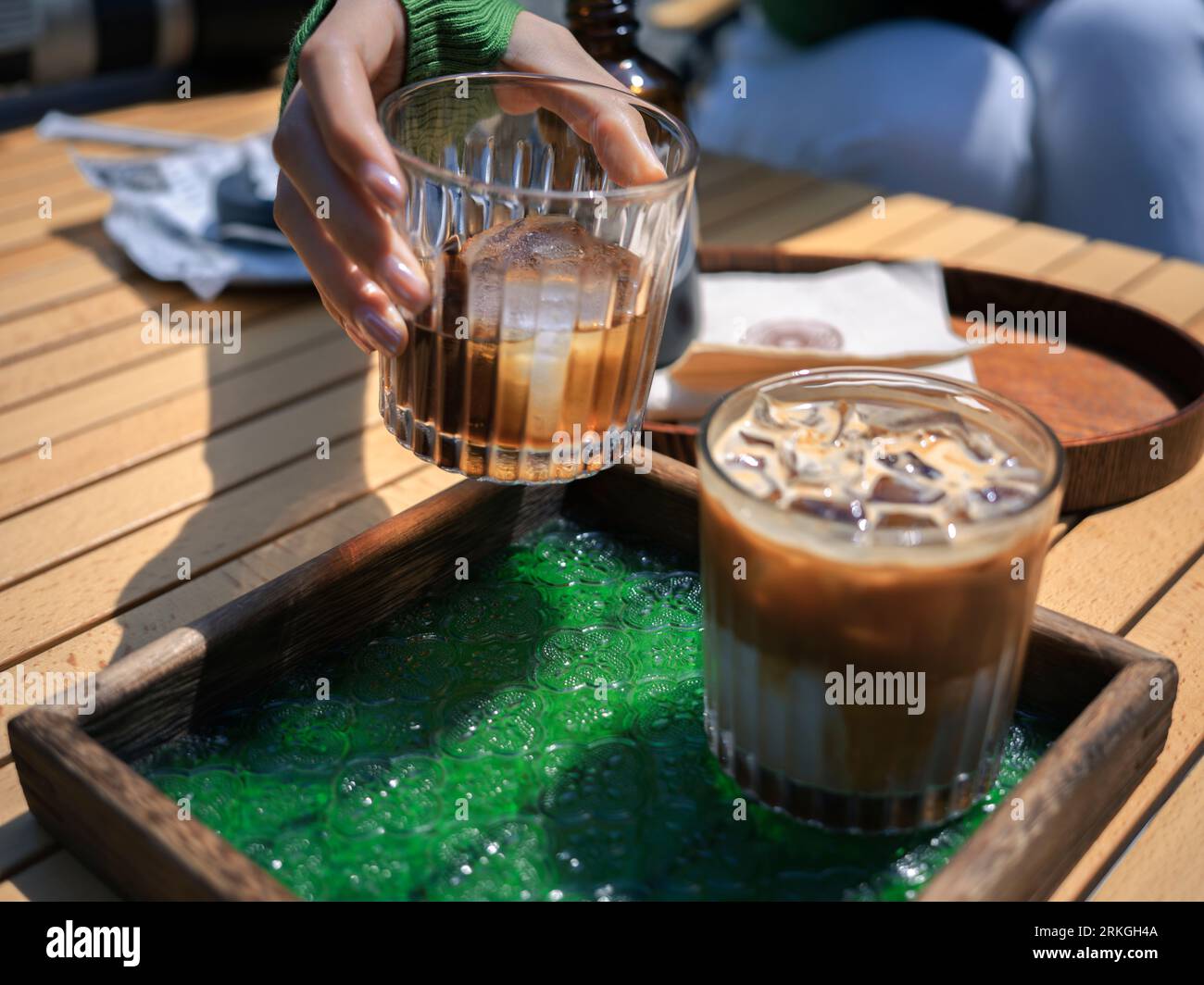 A woman at a restaurant table enjoying a refreshing cold coffee Stock ...