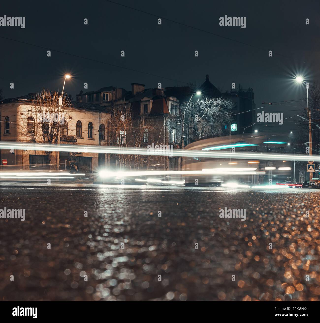 A low-angle shot of a car driving down a street at night, its ...