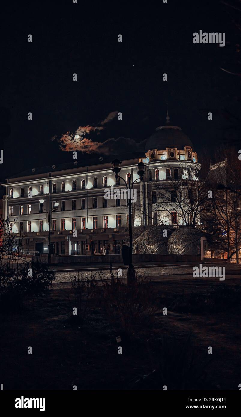 Exterior of a dark building illuminated at night by numerous windows ...