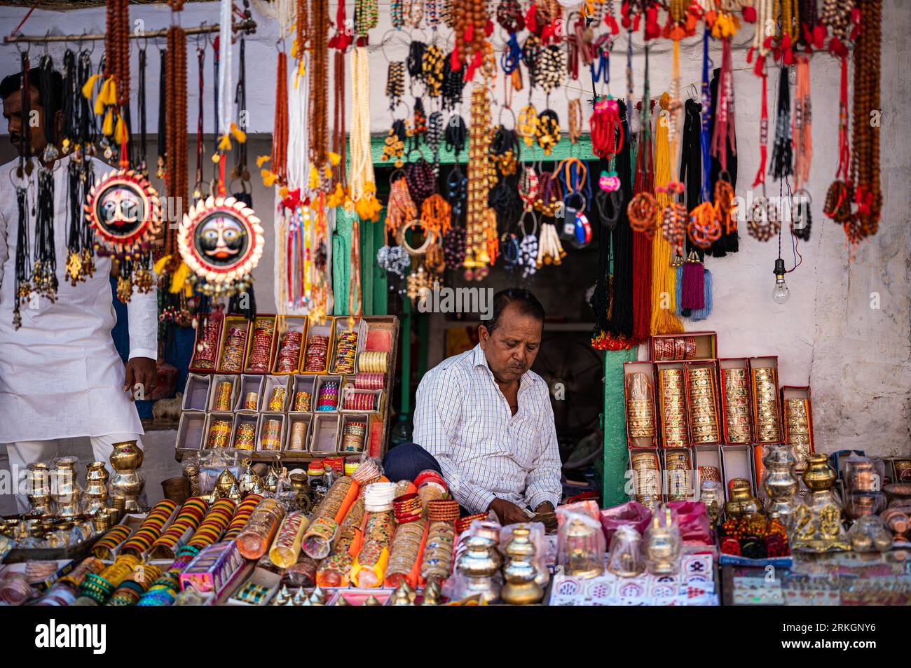 A mature man in a traditional outfit selling some colorful things in ...