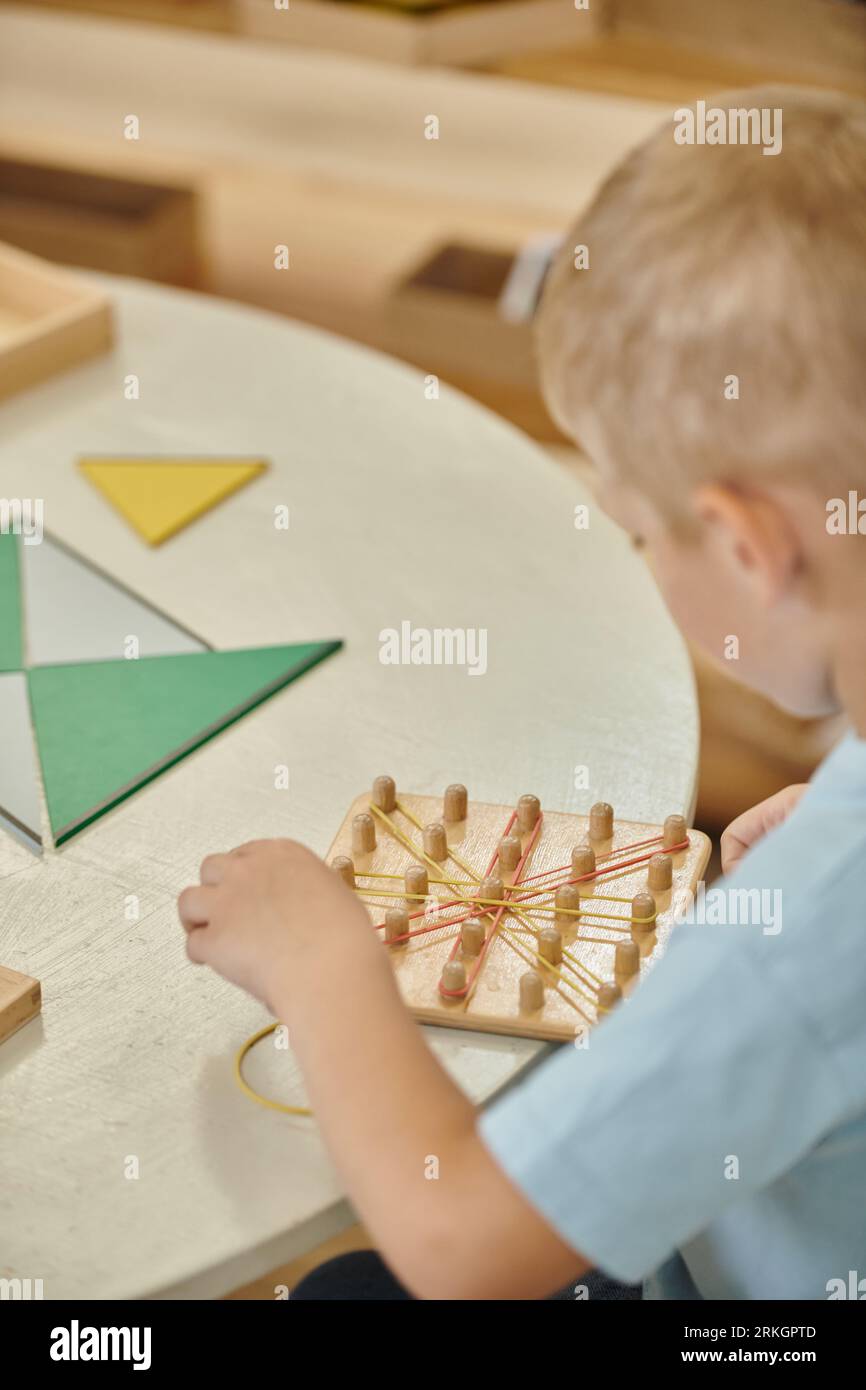 boy playing with rubber bands and wooden sticks during lesson in ...