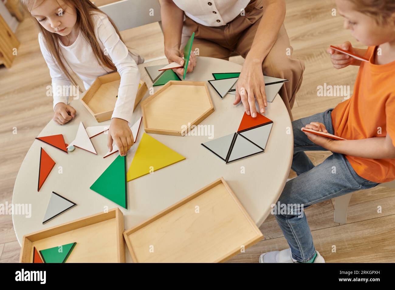 high angle view of teacher and kids playing with triangles on table in ...