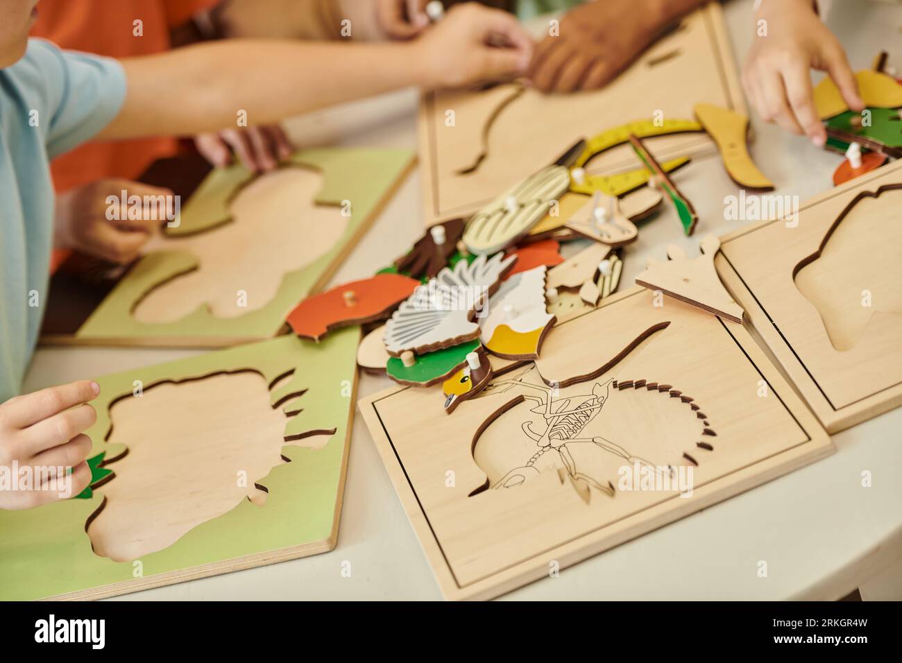 cropped view of interracial kids playing with didactic materials on ...
