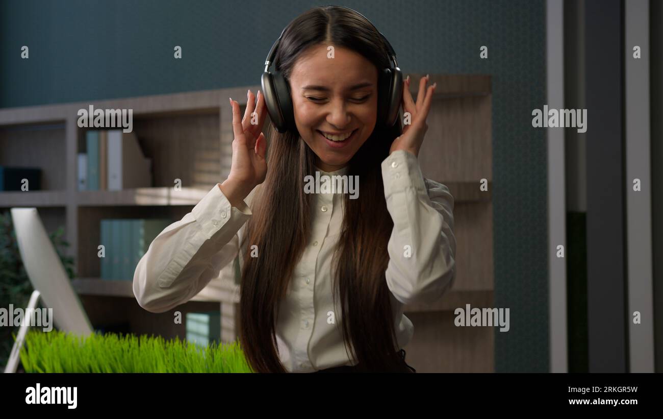 Caucasian girl business woman in headphones listen to music in modern ...