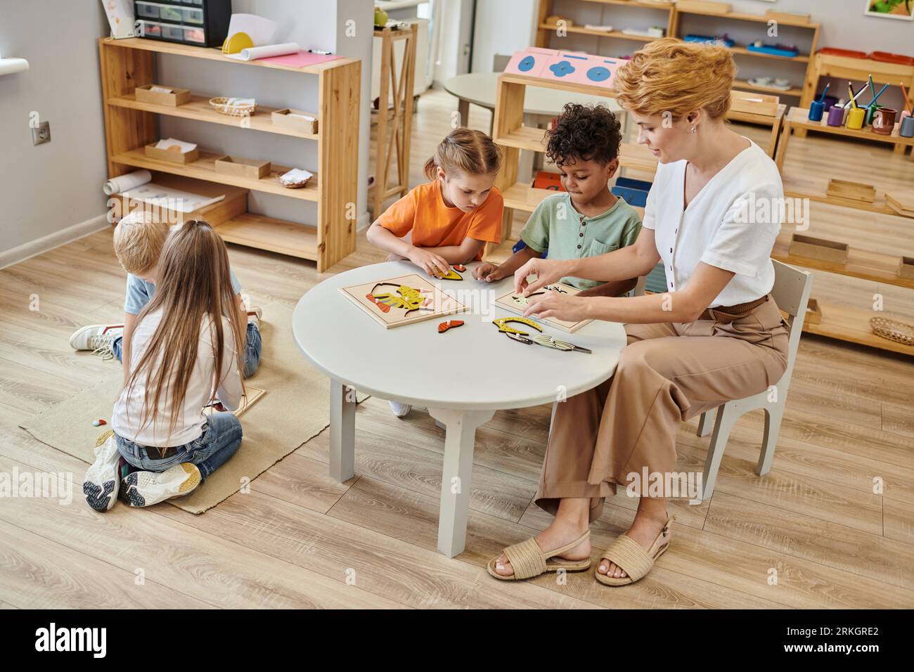 female teacher using didactic montessori material while playing with ...
