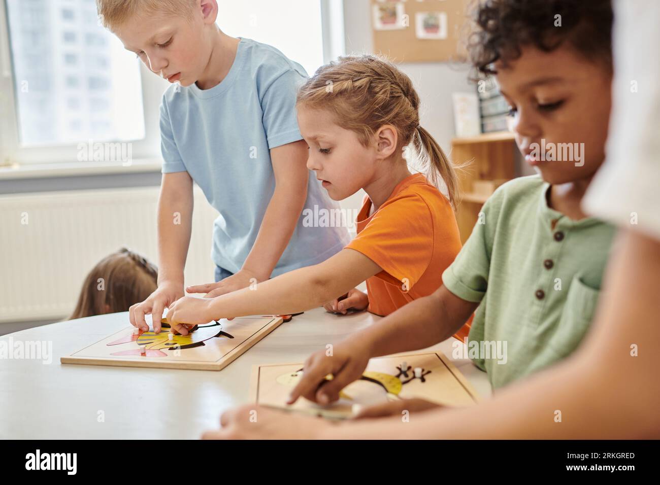 interracial children playing with didactic materials on table in ...