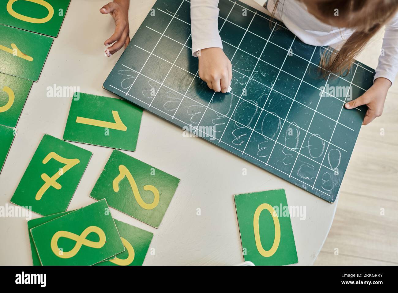 top view of girl writing number zero on chalkboard, learning how to ...
