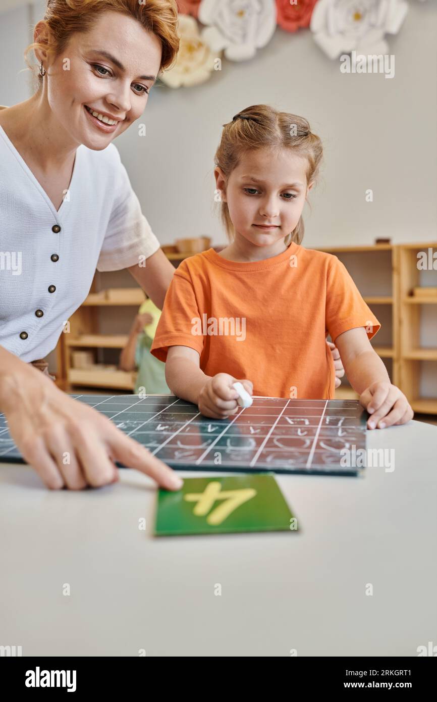 happy teacher pointing at number near smart girl in Montessori school ...