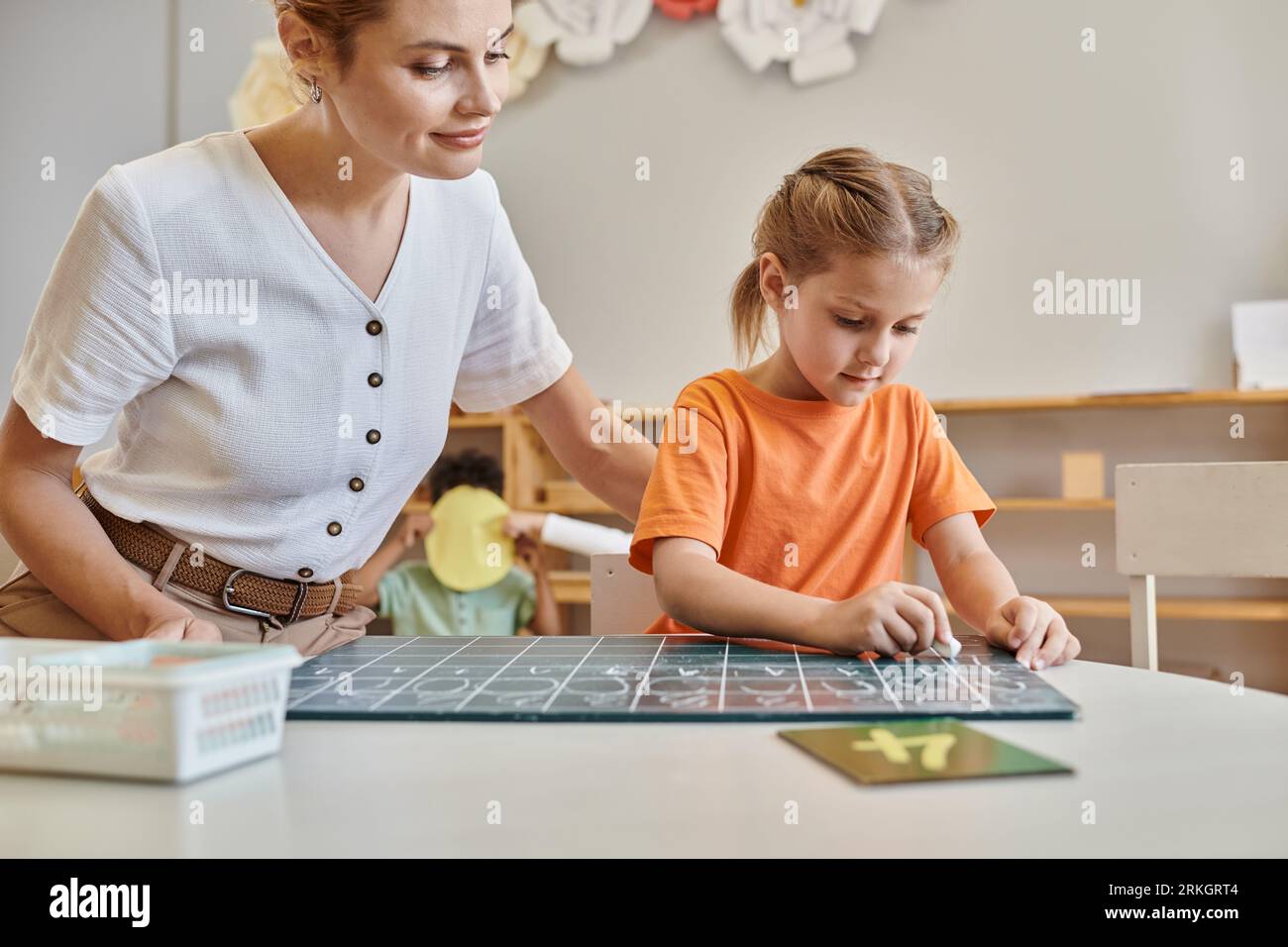 happy teacher observing smart girl in Montessori school, counting ...