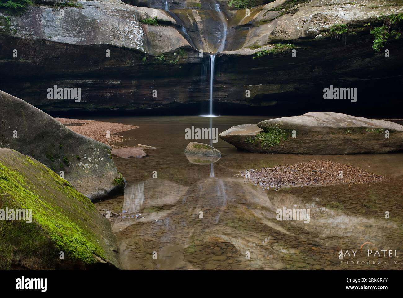 A beautiful waterfall cascading over rocks into a shallow pool of clear ...
