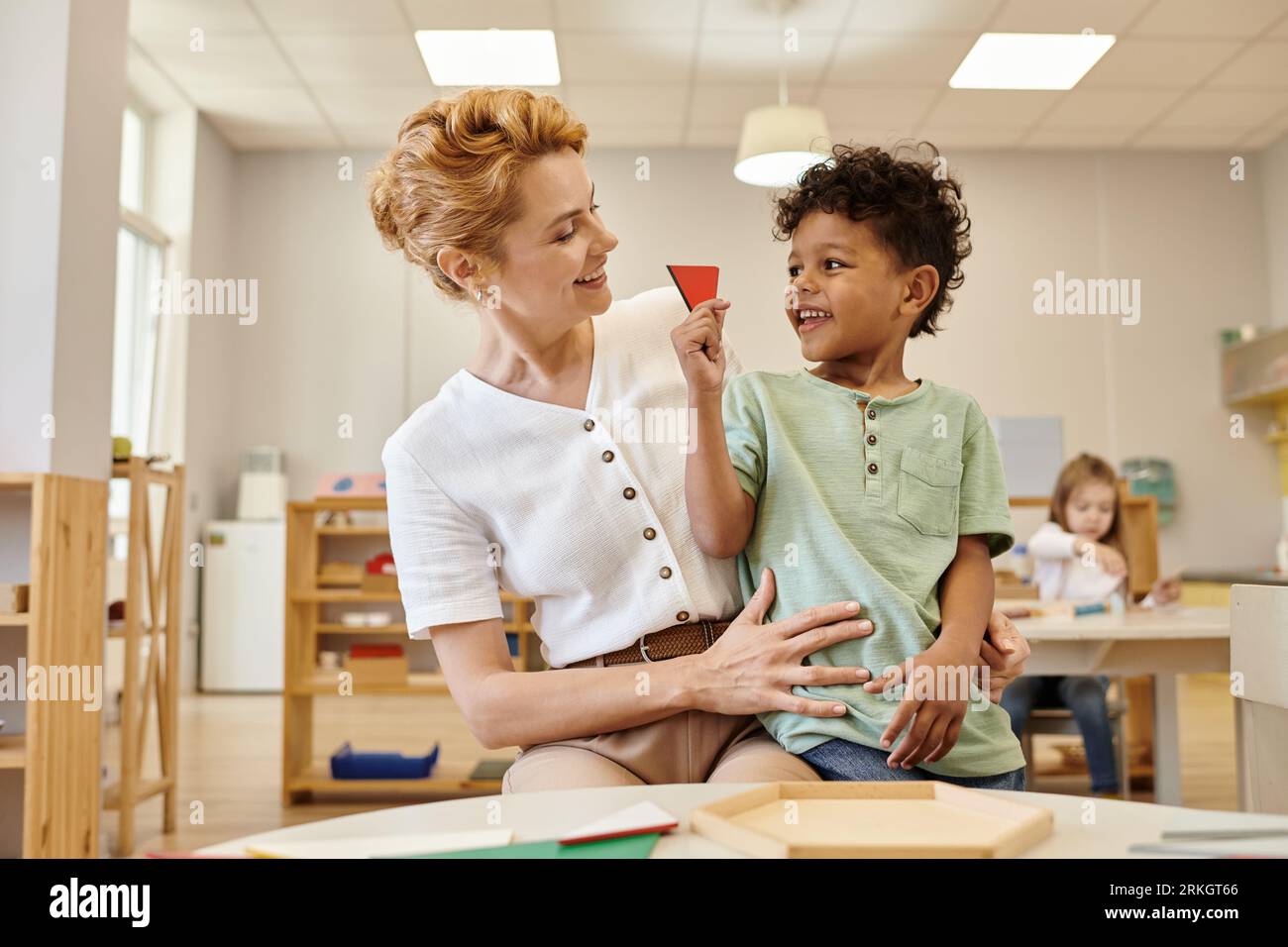 positive african american boy holding triangle near teacher during ...