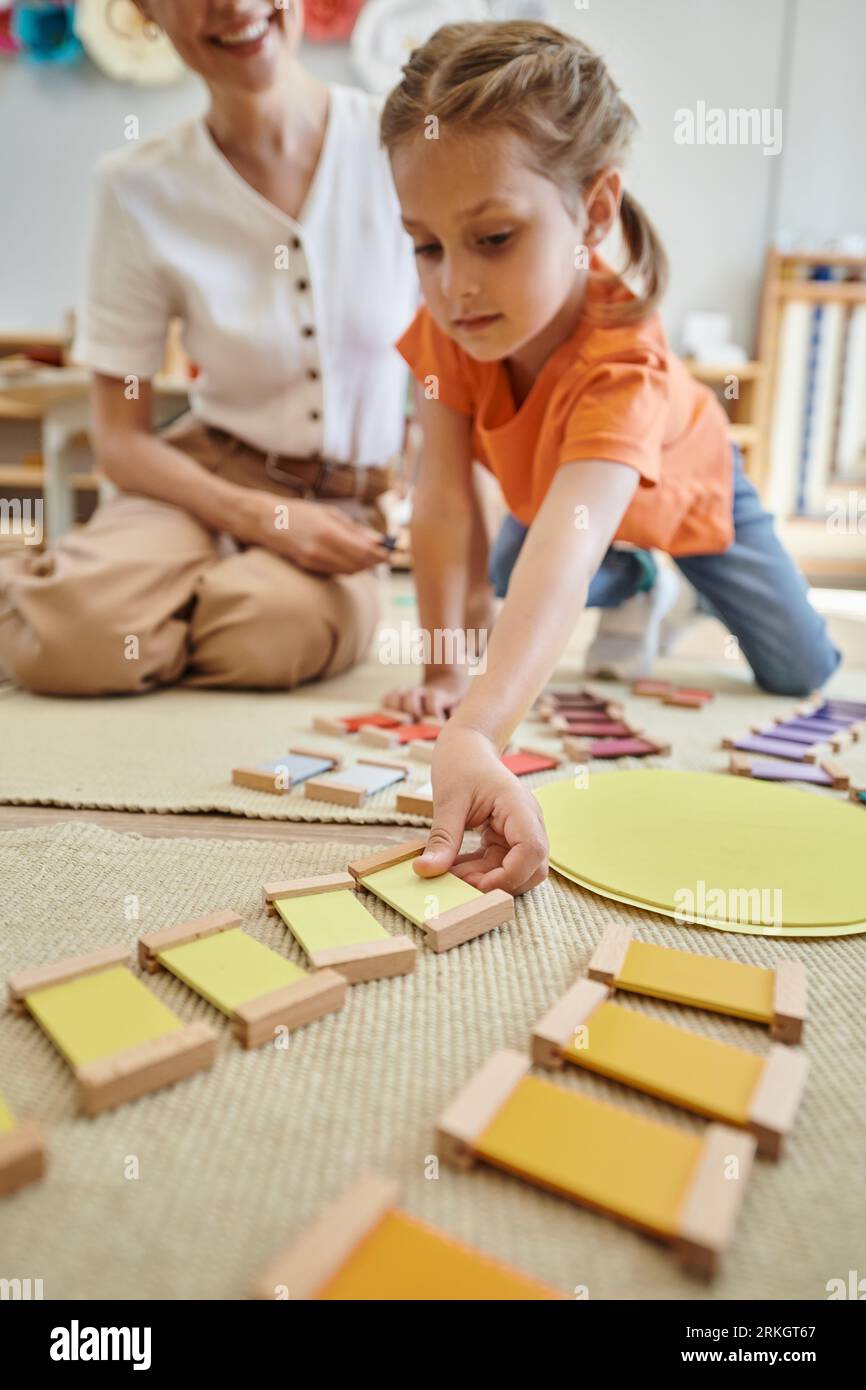 montessori material, cute girl playing color matching game near female ...