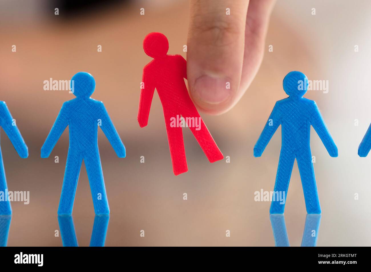 Businessperson's Hand Picking Red Human Figures Amongst Blue Figures In ...