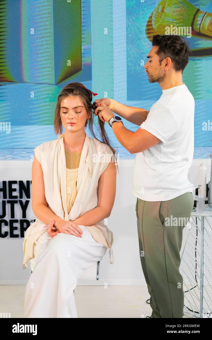 A professional stylist working on a young female model in a hair salon ...