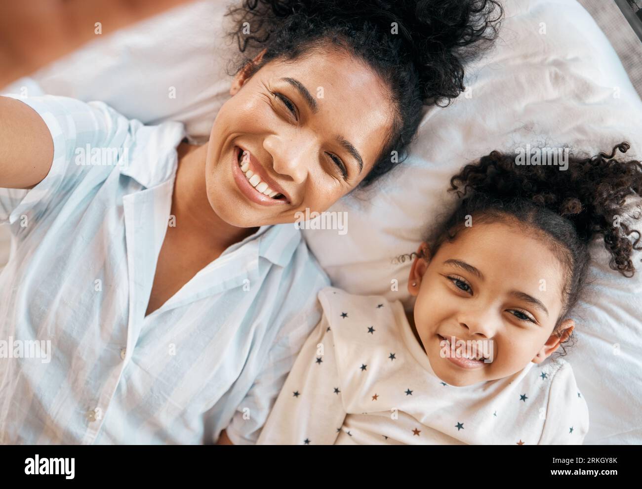 Top view, selfie and mother with girl child on a bed happy, bond and ...