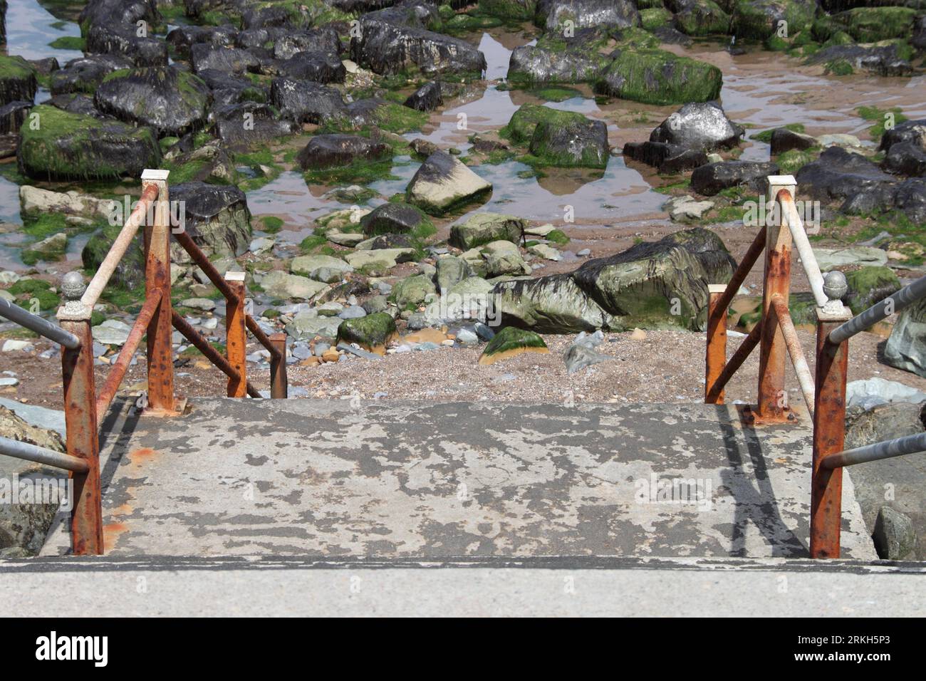 A rugged rocky shoreline featuring a small set of stairs descending ...